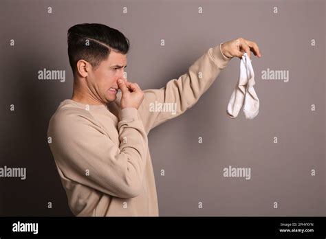 Man Feeling Bad Smell From Dirty Socks On Grey Background Stock Photo Alamy