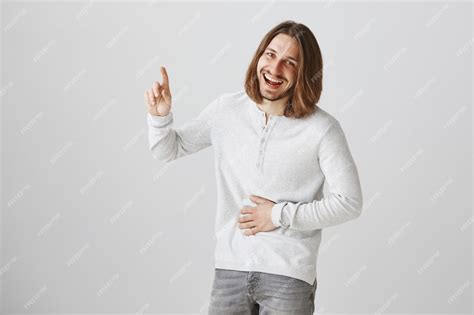 Счастливый бородатый парень смеется над забавным промо указывая вверх на рекламу Бесплатно Фото