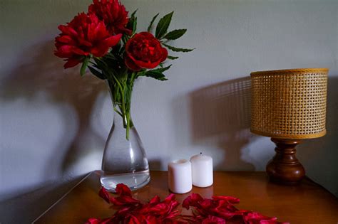 유리 꽃병에 빨간 모란 밀짚 램프 흰색 벽을 가로 질러 나무 Commode에 흰색 촛불 인테리어 디자인 홈 장식 조명 및 그림자 개념 0명에 대한 스톡 사진 및 기타 이미지