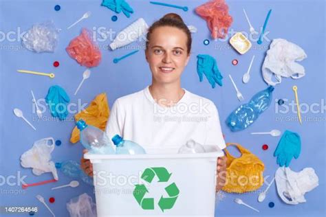 행복한 책임감있는 백인 여성 생태 운동가의 초상화는 재활용을위한 플라스틱 병으로 가득 찬 상자를 가지고 카메라를 보면서 푸른