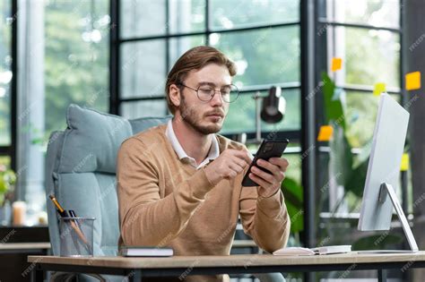 Premium Photo Serious Young Man Programmer Freelancer Sitting At The Desk In The Office