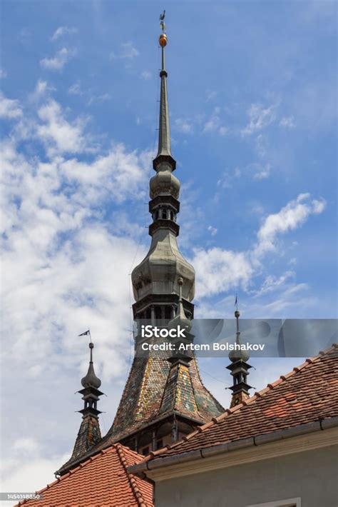 기와 지붕 위로 하늘로 높이 치솟는 풍향계가있는 고딕 양식의 첨탑은 멀리서 시계탑을 더욱 눈에 띄게 만듭니다 시기쇼아라 루마니아 0명에 대한 스톡 사진 및 기타 이미지