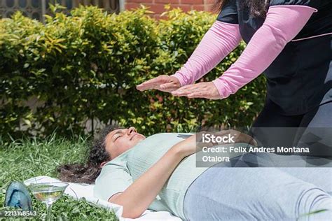정원의 풀밭에 누워 있는 환자에게 레이키 요법을 수행하는 치료사 16 17 살에 대한 스톡 사진 및 기타 이미지 16 17 살 2명 45 49세 Istock