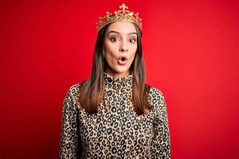 고립 된 빨간 배경에 황금 왕관 여왕을 입고 젊은 아름다운 갈색 머리 여자는 두려워하고 깜짝 표정 두려움과 흥분 얼굴로 충격 공주에 대한 스톡 사진 및 기타 이미지 Istock