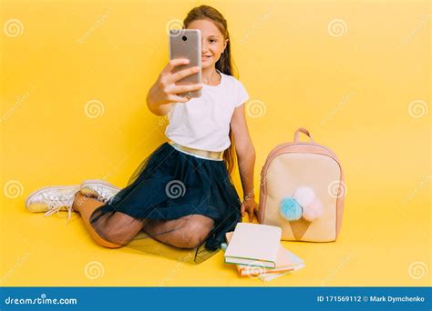 Garotinha Da Escola Tirando Uma Selfie Em Um Smartphone Em Um Plano De Fundo Amarelo Foto De