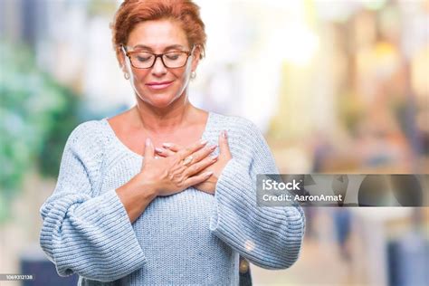 Atrractive 수석 백인 빨강 머리 여자 얼굴에 닫힌된 눈으로 가슴에 손을 감사와 함께 웃 고 고립 된 배경 위에 안경 착용 건강 개념입니다 감사에 대한 스톡 사진 및