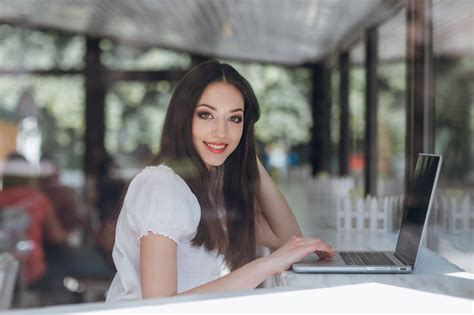 Молодая девушка сидит в кафе с ноутбуком Бесплатно Фото