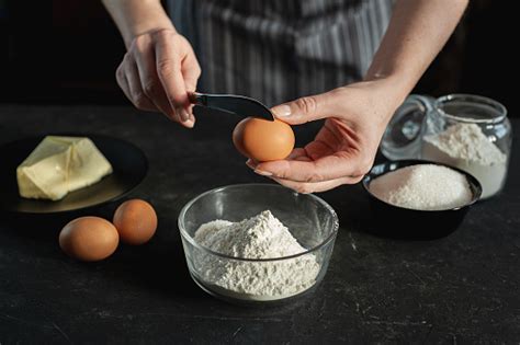 반죽을 준비하는 과정 여자는 계란을 깨고 밀가루 그릇에 추가합니다 여성의 손에 계란과 칼 어두운 배경에 반죽재료 갈색에 대한 스톡 사진 및 기타 이미지 Istock