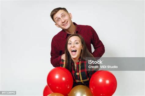 아름 다운 젊은 행복 한 키스 커플 사랑에 여자와 남자와 황금 선물 상자를 들고 제시 하 고 빨강 노랑 흰색 바탕에 생일 축 하 풍선 격리 휴일 파티 개념입니다 2명에 대한