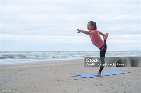 해변에서 요가를 연습하는 아시아 여성 해변의 푸른 요가 매트에서 야외에서 스트레칭을하고 요가를하는 젊은 아름다운 여성 자연에서