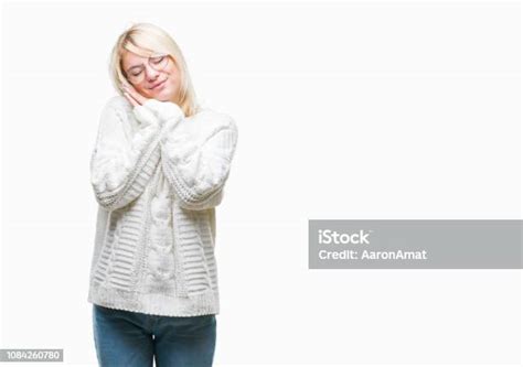 젊은 아름 다운 금발 여자 자 고 피곤 꿈 닫힌된 눈으로 웃 고 하는 동안 함께 손 포즈 격리 된 배경 위에 겨울 스웨터와 안경