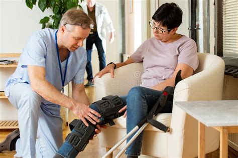 A Male Nurse Helps To Put A Bondage Medical Splint Knee Brace On The Leg Of An Elderly Female