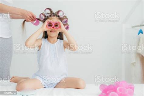 아름다운 작은 아이의 수평 샷은 흰색 배경을 통해 고립 된 카니발에 멋진 헤어 스타일을 가지고가는 그들과 함께 재생 머리에 경기자를 가지고있다 재미 딸 놀이 함께 와 엄마