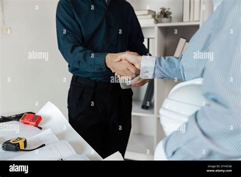 Professional Engineers Collaborating On Architectural Project With Blueprints And Tools In