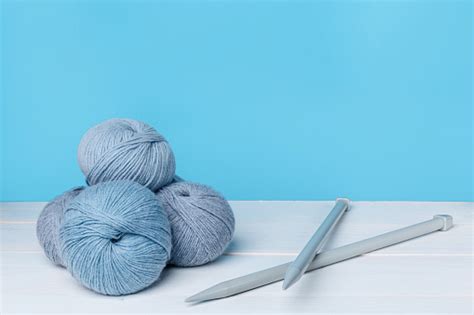 파란색 배경흰색 보드에 실의 모직 Skeins 이탈리아 앙고라에서 스레드의 공 뜨개질 프로젝트가 진행 중입니다 원사와 뜨개질 바늘의 공뜨개 조각 0명에 대한 스톡 사진 및