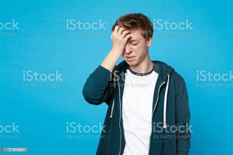 스튜디오에서 파란색 배경에 고립 된 머리에 손을 퍼 팅 눈을 유지 하는 캐주얼 의류에 우는 불쾌 한 젊은 남자의 초상화 사람들은 진심으로 감정 라이프 스타일 개념입니다 복사
