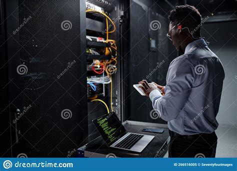 Network Engineer Using Laptop While Setting Up Servers In Data Center