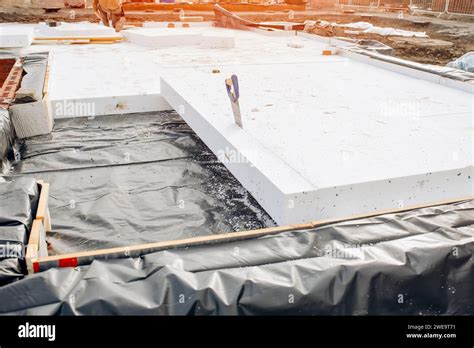 Builder Placing Polystyrene Insulation Boards On Waterproofing Membrane During Floor
