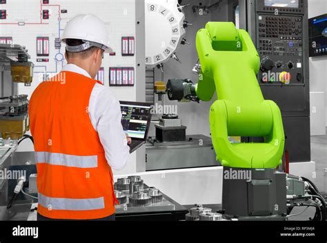 Engineer Using Laptop Computer Control Automatic Robotic Hand Machine Tool With Cnc Machine In