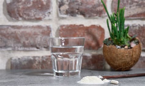 콜라겐 단백질 파우더 물 한 잔 옆에 있는 돌 탁자 위에 나무 숟가락으로 하이드로분해 추가 단백질 섭취 피부 뼈 관절의 아름다움과 건강을 위한 천연 보충제 클로즈업 0명에