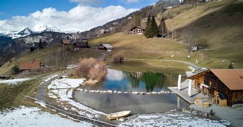 경치 고요한 관광 구름 그림 같은 농촌의 눈 드론 촬영 마을 목가적인 목조 주택 반사 반사 호수 베르네 알프스 베르네 제 오버 란 트 베른 봄