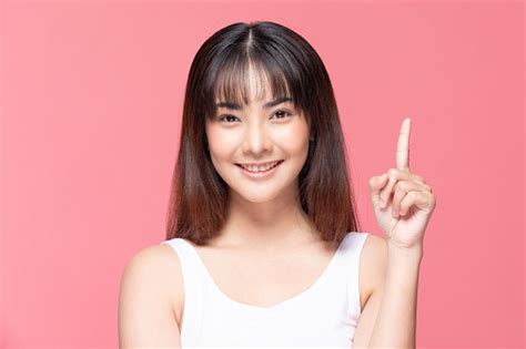 젊고 아름다운 아시아 여성은 깨끗하고 신선한 피부행복과 긍정적 인 감정으로 쾌활한 미소 핑크 배경 뷰티 화장품 및 스파