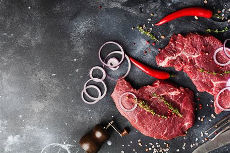 어두운 슬레이트 또는 콘크리트 배경에 향신료 양파 칠리를 곁들인 두 개의 생 소고기 스테이크 위쪽 보기 가루로 빻은에 대한 스톡 사진 및 기타 이미지 Istock