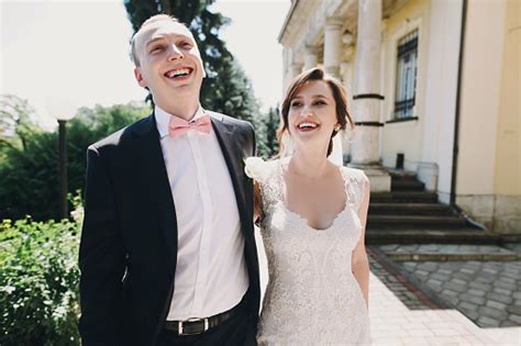 화려한 신부 놀라운 드레스에서와 세련 된 도시 거리에서 웃 고 걷는 신랑 밝은 야외에서 시간을 즐기고 아름 다운 행복 한 웨딩 커플 낭만주의 순간 2명에 대한 스톡 사진 및