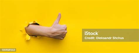 오른쪽 여성의 손은 엄지 손가락 위로 제스처 를 보여줍니다 노란색 종이에 찢어진 구멍 긍정적 인 태도 승인 및 칭찬의 개념