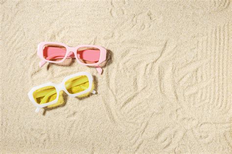 햇빛에 모래 배경에 세련된 분홍색과 노란색 선글라스 컬러 유리가 있는 여름 패션 컬렉션 안경 여름 세일 개념입니다 상위 뷰
