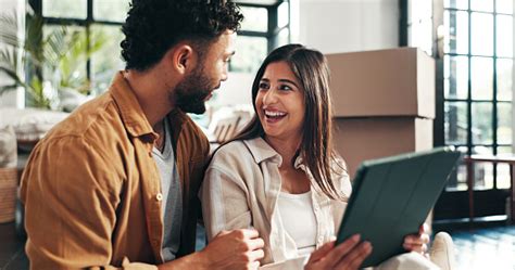 모기지 미소 태블릿은 계획 또는 부동산 투자를 위해 함께 새 집에서 부부와 함께합니다 상자 개발 또는 아파트 거실에서 남자와 여자와의 사랑 부동산 또는 개조 25 29세에