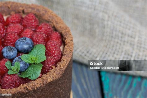 크림 치즈를 곁들인 초콜릿 케이크를 굽지 않습니다 라즈베리 블루베리 민트 잎으로 장식되어 있습니다 소나무 보드의 표면에 검은 색과 녹색으로 칠해진 0명에 대한 스톡 사진 및