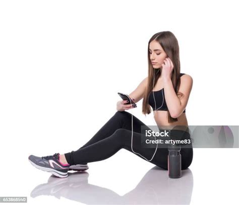 흰색 배경 위에 이어폰으로 음악을 듣고 젊은 선수 여자의 초상화 매력적인 피트 니스 소녀 스마트폰 이온 스튜디오에 채팅입니다 Mp3 플레이어에 대한 스톡 사진 및 기타