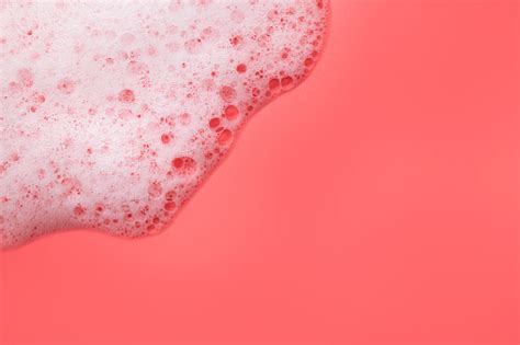 분홍색 배경에 거품이 있는 하얀 거품의 질감 세척 위생 샴푸 비누 목욕 젤 무스를위한 화장품 거품 최소한의 미용 및 의료 배경 플랫 레이 건강관리와 의술에 대한 스톡 사진