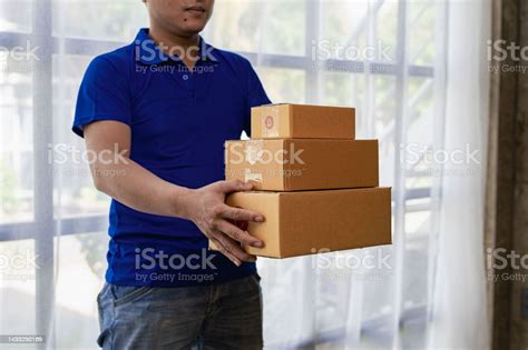 파란색 모자와 파란색 티셔츠를 입은 행복한 청년이 흰색 배경에 고립 된 노란색 상자를 들고 서있는 사진 배달 개념 건강 진단에