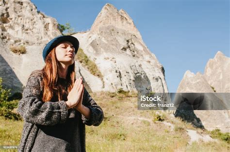 히 프 보기화창한 날에 접힌된 손을와 아름 다운 산과 언덕의 배경 닫는 눈 모자와 회색 스웨터에 아름 다운 젊은 여자 묵상 건강한 생활방식에 대한 스톡 사진 및 기타 이미지