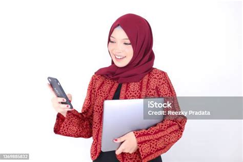 젊은 아시아 이슬람 여자는 서 서 서 웃고 얼굴 때 노트북을 들고 휴대 전화에 보고 노트북에 대한 스톡 사진 및 기타 이미지 노트북 사람 얼굴 서 있기 Istock