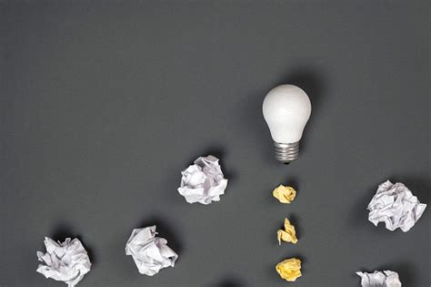 회색 배경에 구겨진 사무실 용지와 흰색 전구와 새로운 아이디어 개념 세션 개념을 브레인스토밍하는 동안 창의적인 솔루션 플랫 레이 상단 보기 복사 공간 개념에 대한 스톡 사진