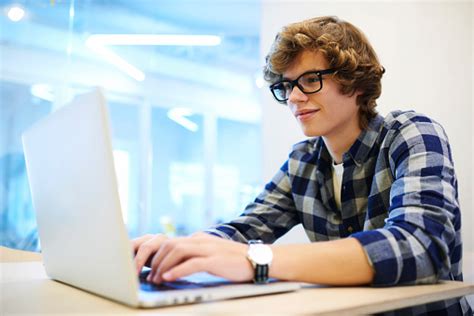 현대 노트북 컴퓨터 교실에 앉아 주말에 여행 투어를 준비 하는 소셜 네트워크에서 가장 친한 친구와 채팅의 키보드에 입력 하는 텍스트 메시지의 잘생긴 젊은 유학생 Cd