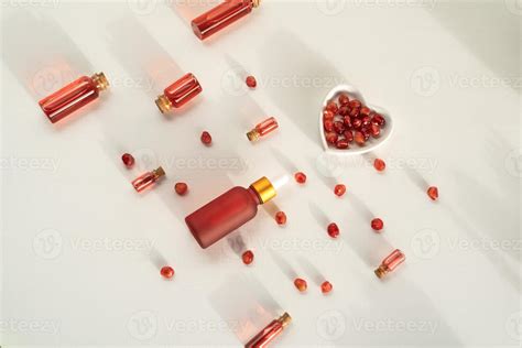Red Dropper Bottles Of Pomegranate Serum Or Oil For Face And Body Lying On A White Table