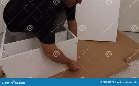 A Man Is Assembling A Bookshelf Attaches The Side Walls With A Key