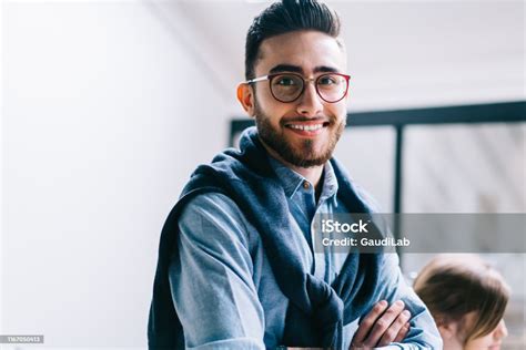 카메라에 미소 시력 교정을위한 안경에 성공적인 젊은 기업가의 절반 길이 초상화 공식적인 착용에 긍정적 인 사업가와 현대 사무실에 서 손을 교차 감독에 대한 스톡 사진 및