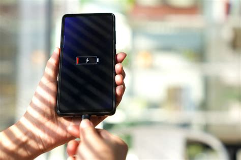 화면에 배터리 부족 표시기가 있는 전화기를 들고 카페에서 휴대폰 배터리를 충전하는 여성 손 Usb 케이블에 대한 스톡 사진 및 기타 이미지 Usb 케이블 가정 생활