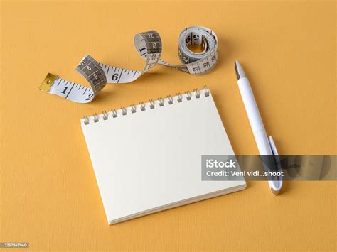 노란색 텍스처 배경에 센티미터 와 인치 측정 테이프의 복사 공간 흰색 펜및 롤종이 메모장을 엽니 다 건강한 식습관 다이어트 체중 감량 몸매 슬림의 개념 공란에 대한 스톡