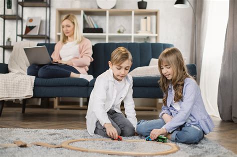 어린 엄마는 소파에서 노트북을 사용하여 휴식을 취하고 어린이 아들 딸은 장난감 자동차 놀이를 즐깁니다 3 명에 대한 스톡 사진 및 기타 이미지 Istock