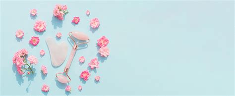 홈 스파용 페이셜 마사지 키트 장미 싹과 파란색 파스텔 배경에 장미 석영으로 만든 얼굴 롤러와 구아 샤 마사지 자연 치료 개념