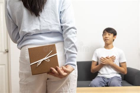 Young Asian Woman Hide A T Box With Man Sitting On A Sofa In Living