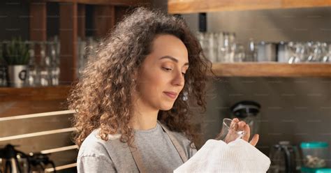 작업복을 입은 예쁜 젊은 웨이트리스는 레스토랑이나 카페의 바 카운터에 서 있는 동안 흰색 면 냅킨이나 수건으로 유리를 청소합니다 사진 Unsplash의 바 카운터 이미지