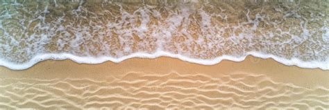 Aerial View Of Waves Gently Crashing On Sandy Beach Shoreline Pattern