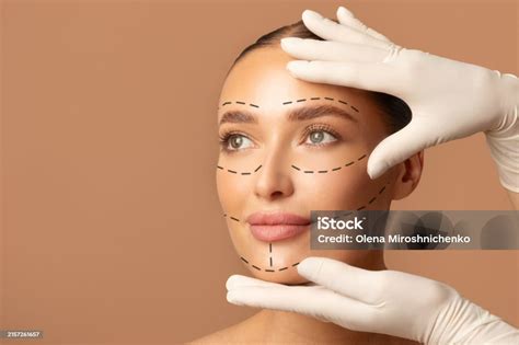 젊은 여성과 성형 외과 의사의 초상화 베이지 색 스튜디오 배경 얼굴 성형 수술 준비 위에 여성의 얼굴에 표시를 만드는 모습 2